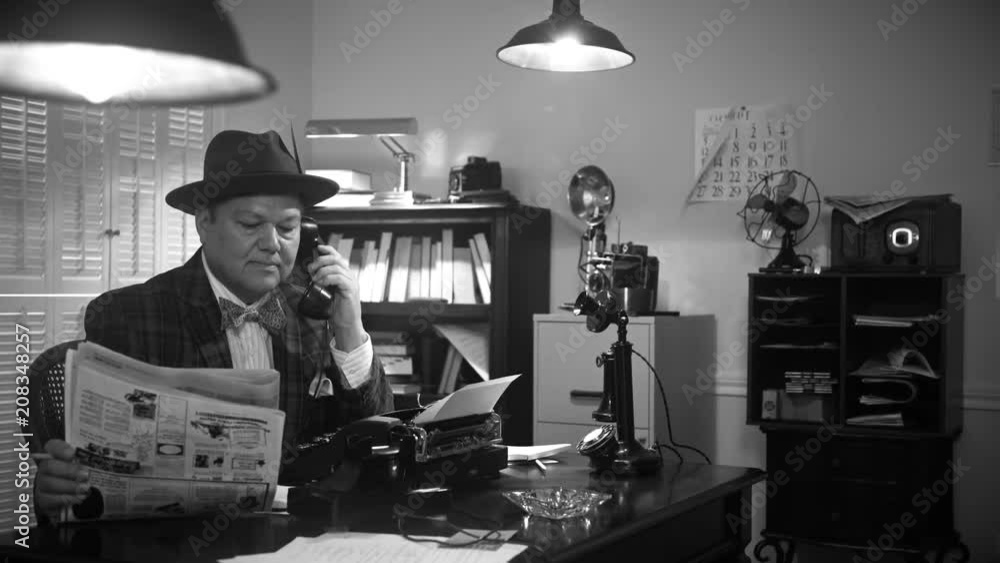 Scene tracks around a 1940s era newsroom with a reporter talking on ...