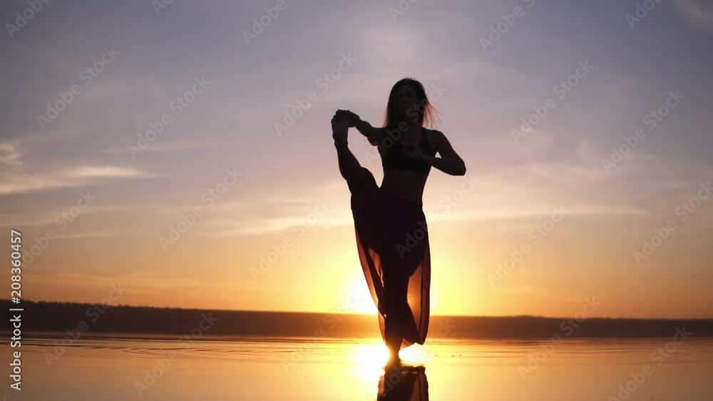 Silhouette yoga woman practicing yoga posture on sea coast at beautiful ...