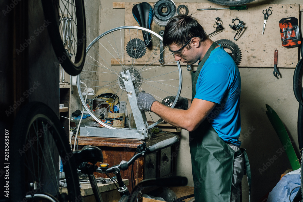 Competent bicycle mechanic in a workshop repairs a bike. Stock Photo ...