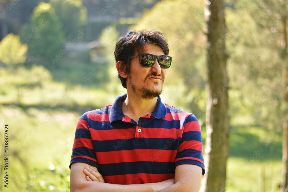 Young man's outdoors portrait looking at the camera with natural green ...