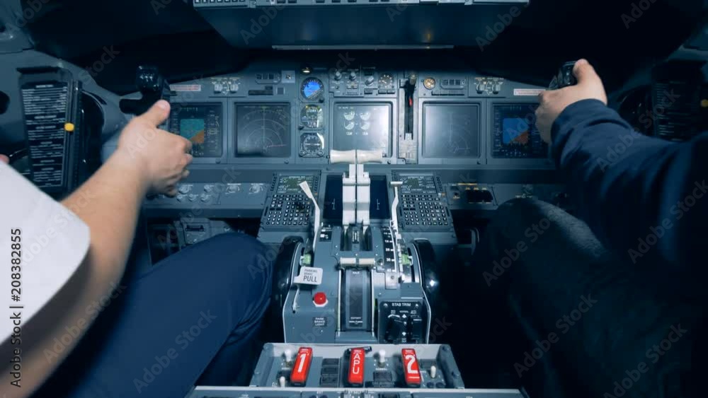 Two men are sitting in a cockpit of a flight simulator and are ...
