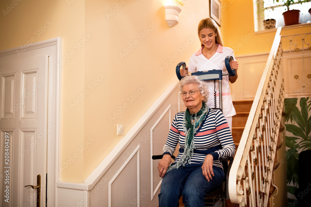 Smiling old lady, happy while nurse helps her to climb to the stairs ...