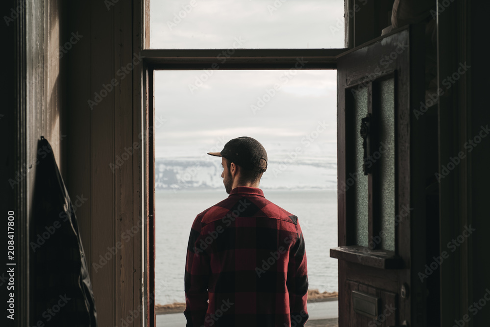 Rear view of a man standing at doorway and looking at view Stock Photo ...