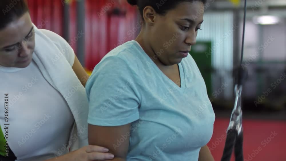 Tilt up of middle-aged woman with towel fixing posture of black female ...