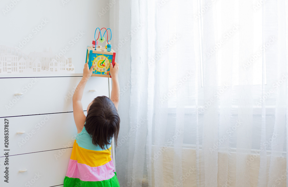 A little girl 3 years stretches to get an educational toy from a high ...
