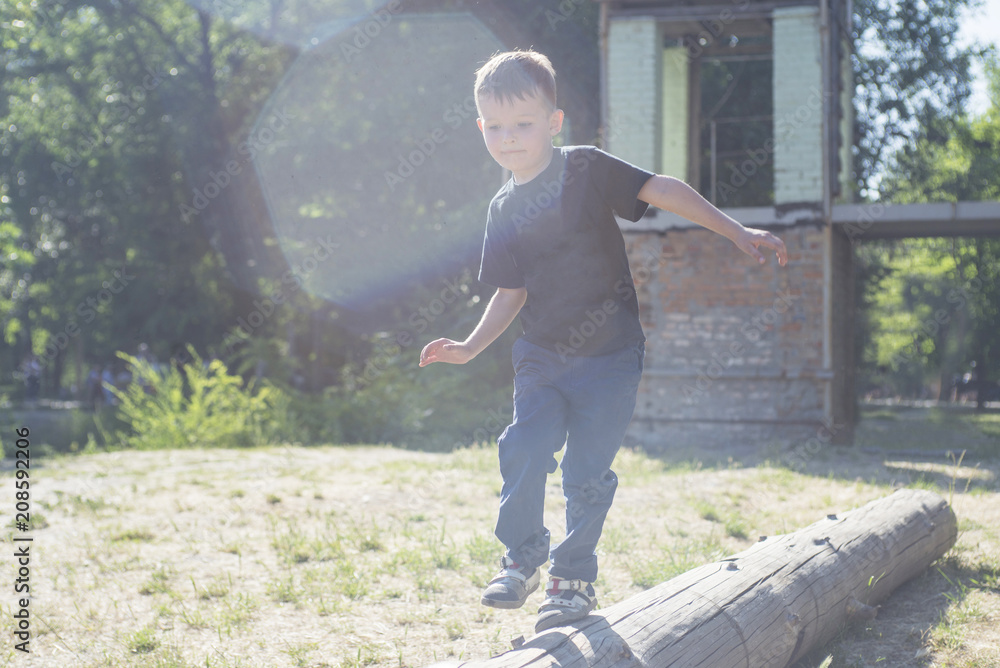 Little boy walking on a log in the park. child on the balance beam ...