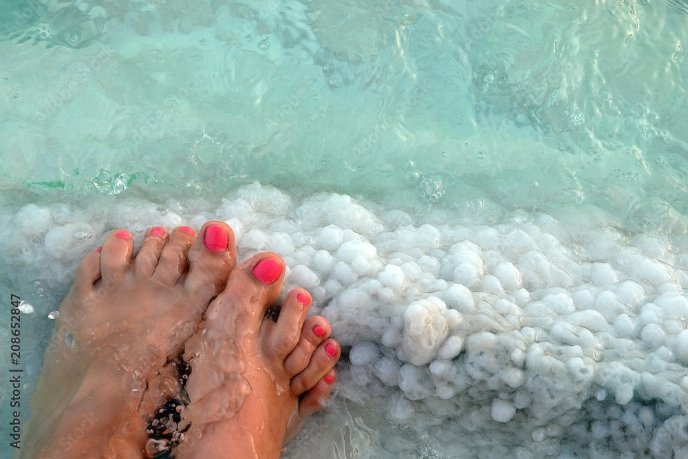 Female feet with manicure on stone, covered with salt formations ...