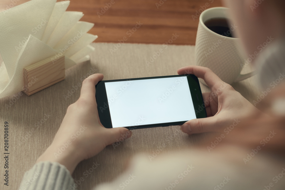 Girl watching video or play game on mobile phone in horizontal position ...