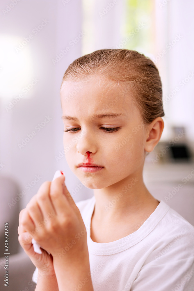 My blood. Sad cheerless girl looking at the paper tissue while having ...
