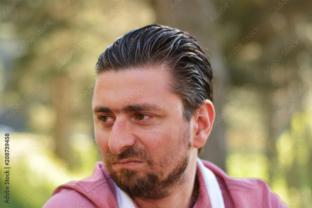 Young man's outdoors portrait looking at the camera with natural green ...