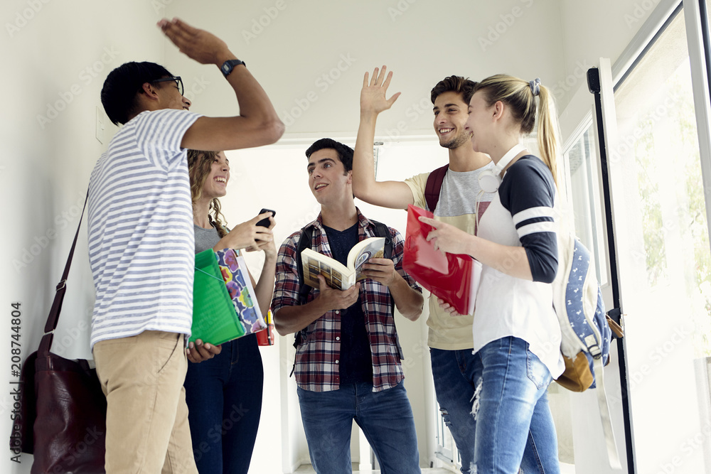 Students giving each other a high-five in corridor Stock Photo | Adobe ...