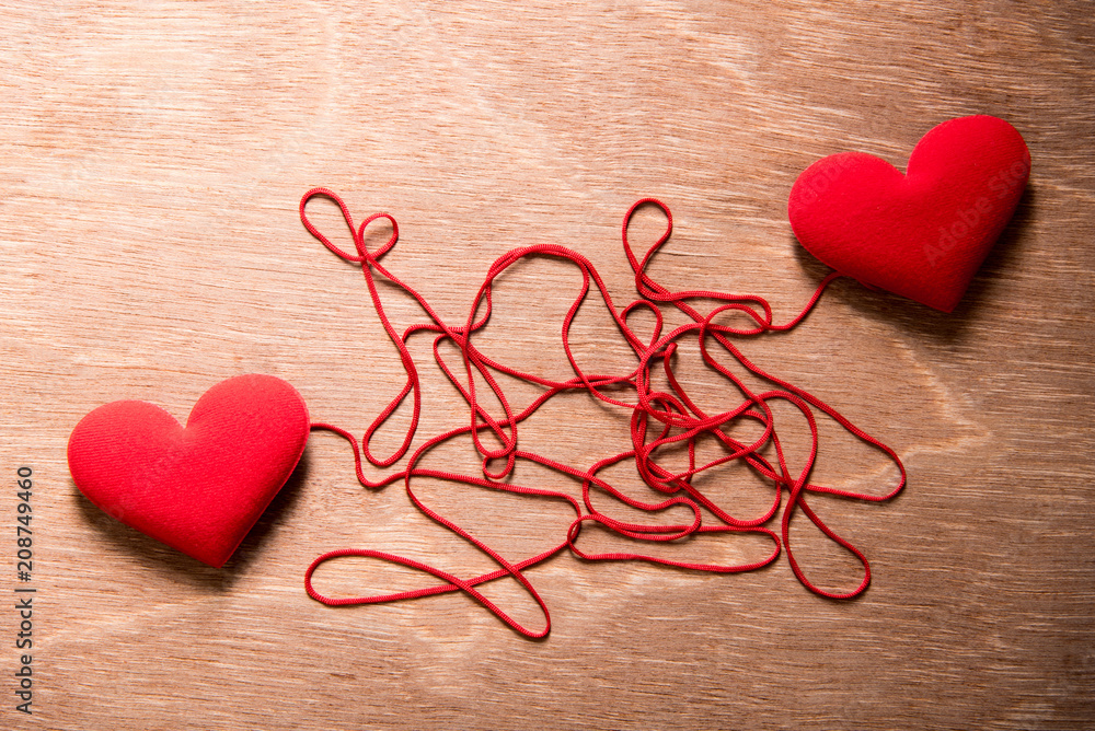 two red heart and complex red string connect together on wood ...