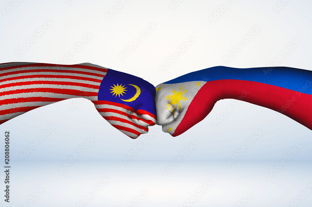 Fist bump of Malaysian and Filipino flags. Two hands with painted flags ...