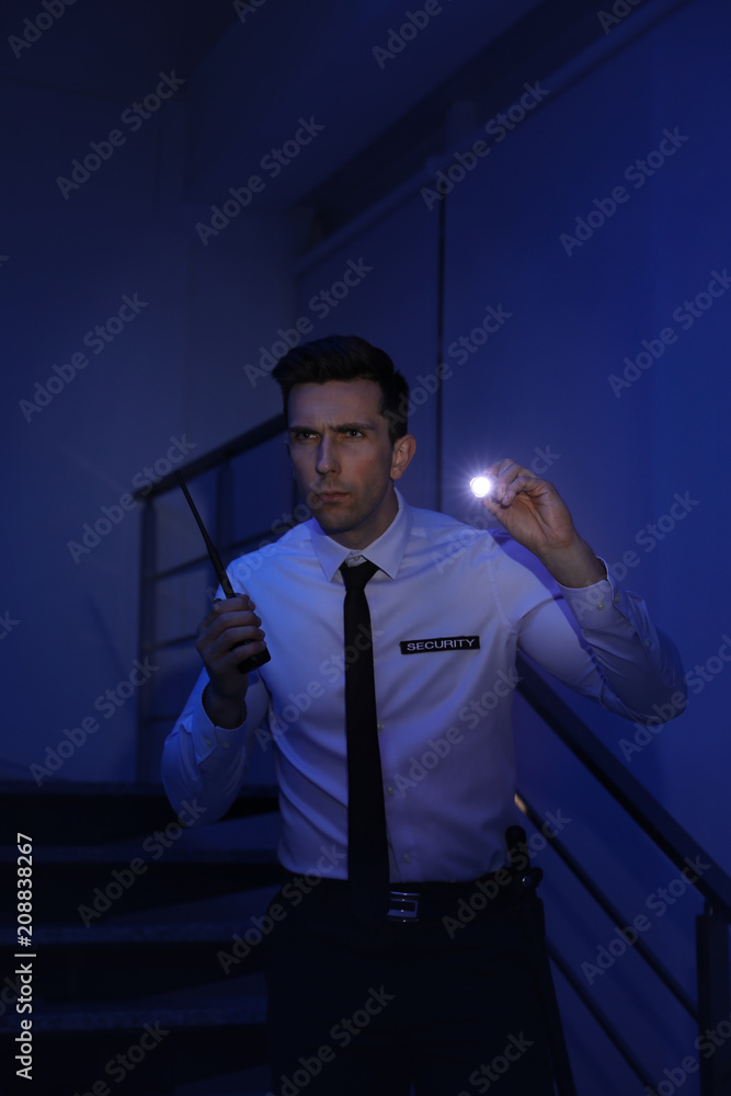 Male security guard with flashlight and portable radio transmitter in ...
