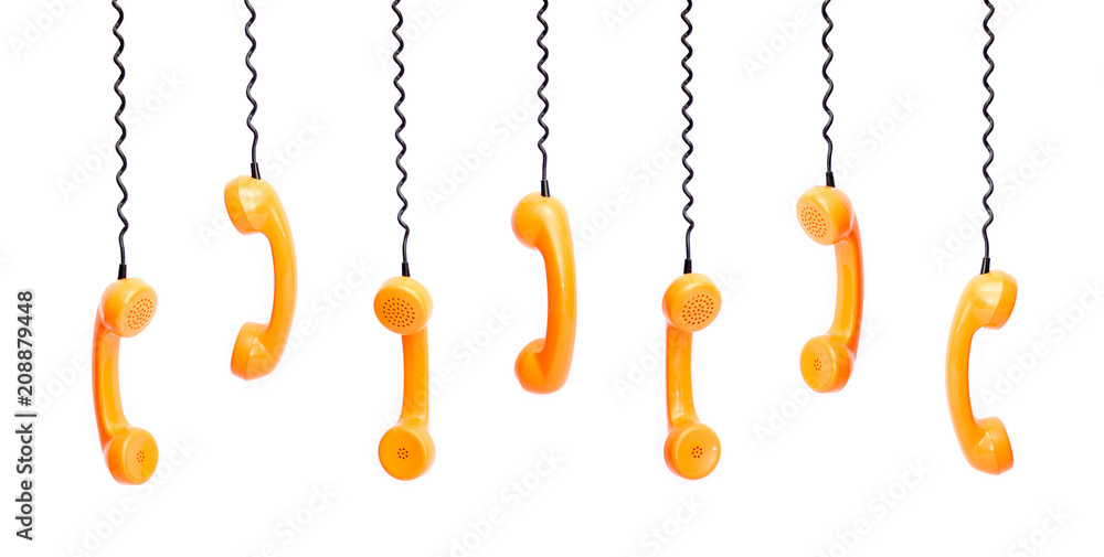 Handset piece from an old phone suspended by the phone cord, isolated ...