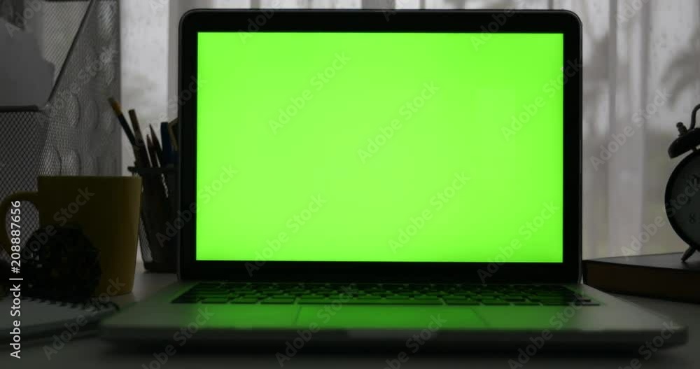Laptop with green screen. Dark office. Perfect to put your own image or ...