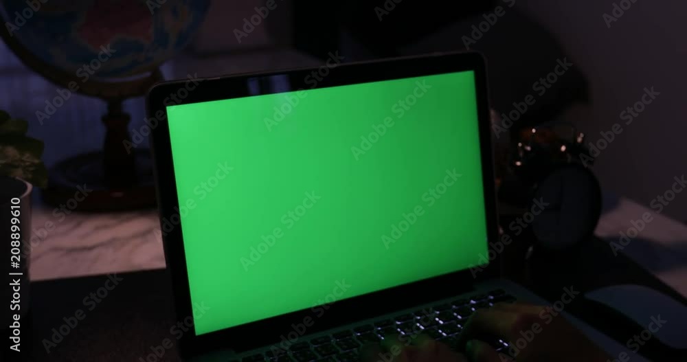 Laptop with green screen. Dark office. Dolly in . Perfect to put your ...