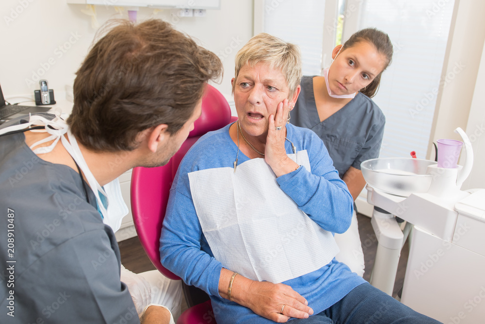 Eine Frau sitzt mit Zahnschmerzen auf dem Behandlungsstuhl beim Zahnarzt Stock Photo | Adobe Stock