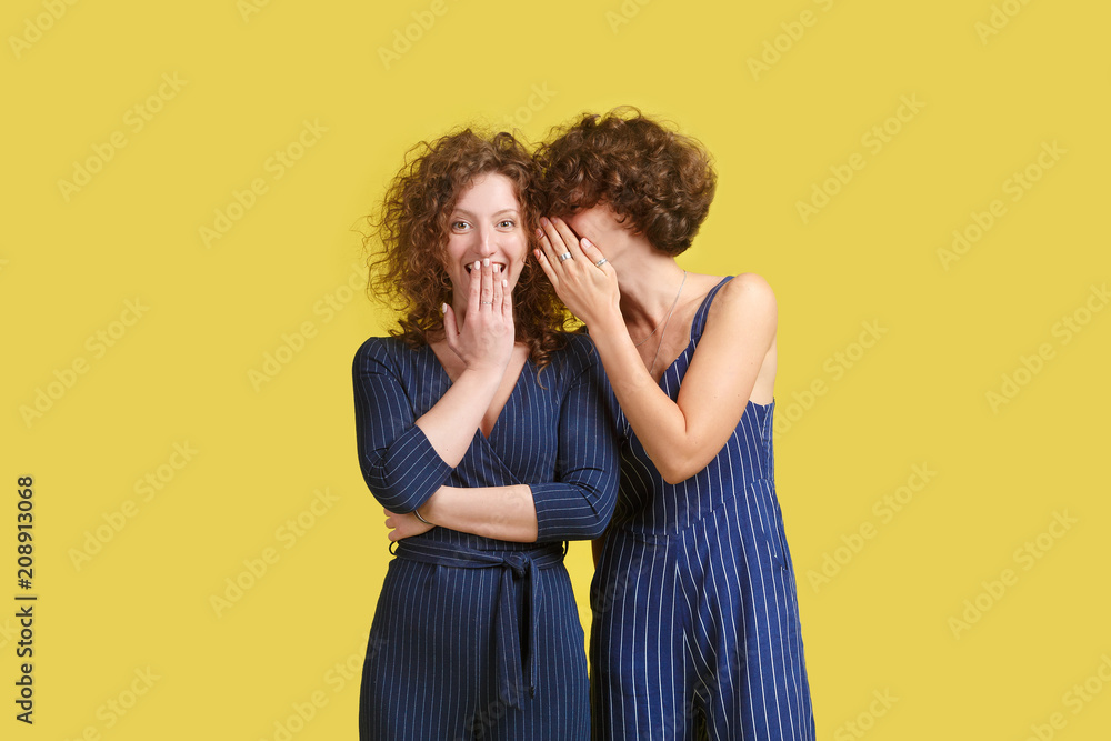 Handsome young curly European female in blue overall whispering ...