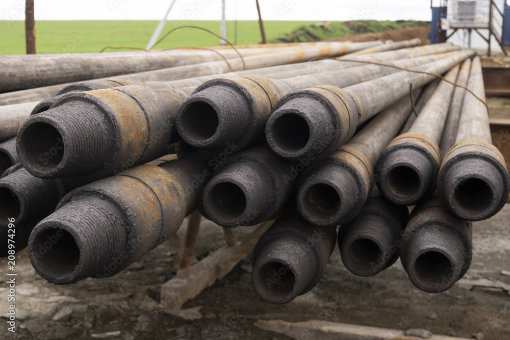 Oil drill pipe. Laid out drilling pipes at a well site.Well Drilling ...