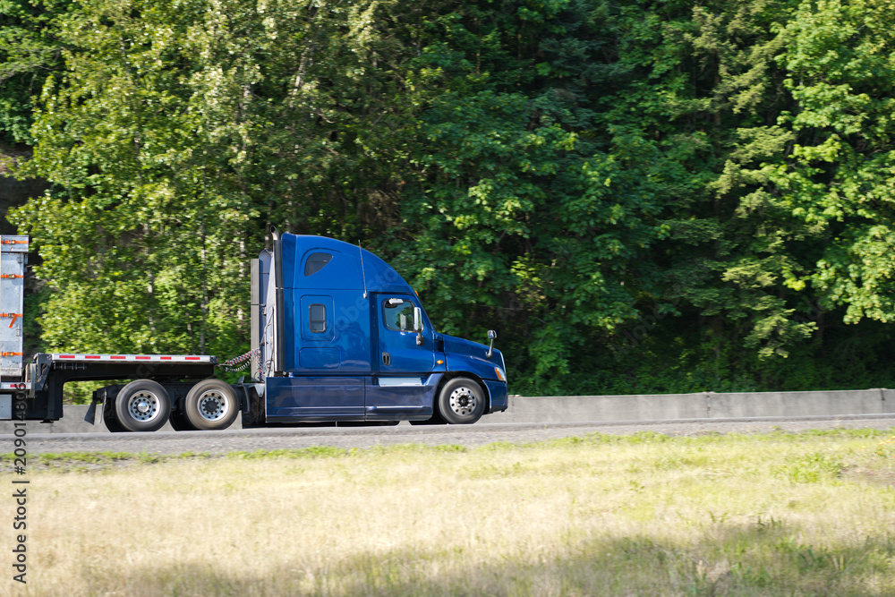 Blue big rig semi truck profile going with semi trailer on the road ...