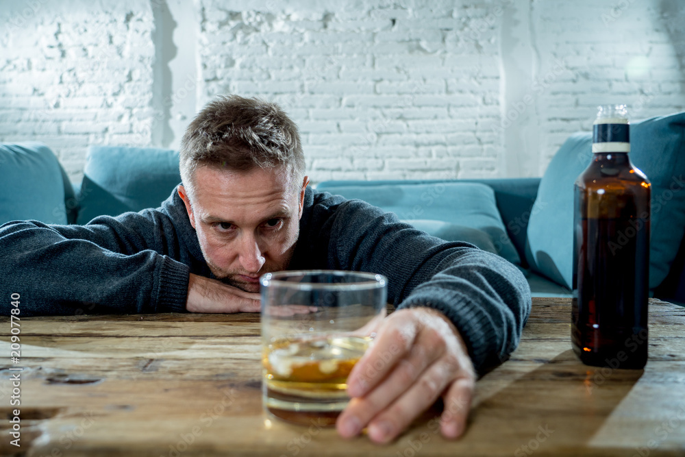 young drunk man depressed and sad drinking whiskey at home Stock Photo ...