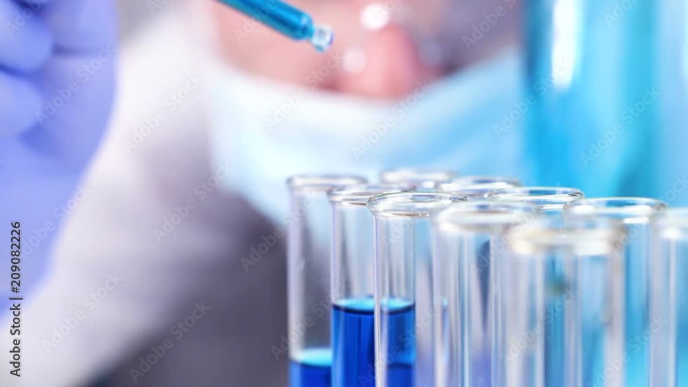 Scientist with pipette in laboratory drop liquid in test tube. Close up ...
