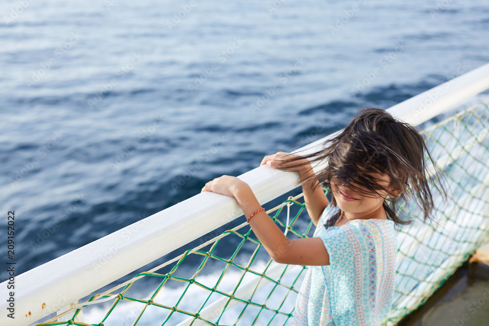 Asian little girl lying on the railing. On the cruise ship, the sea ...