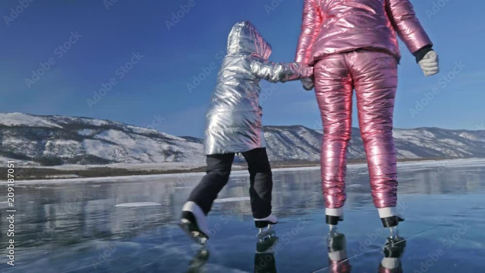 Family is ice skating at day. Girls to ride figure ice skates in nature ...