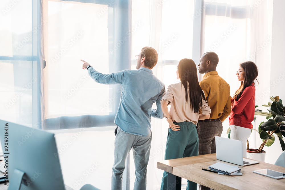 back view of multiethnic business colleagues looking out window in ...