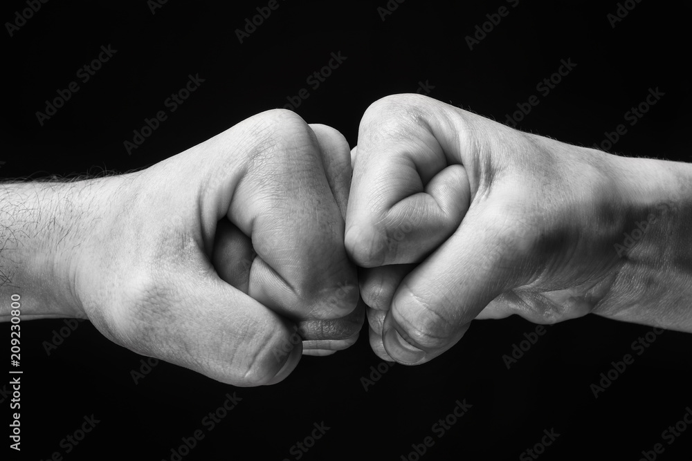 black and white image close up clash of two fists on black background ...