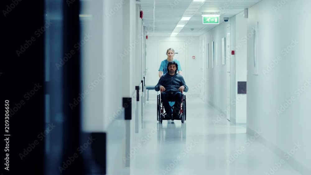 Female Nurse Pushing Patient in the Wheelchair Through the Hospital ...