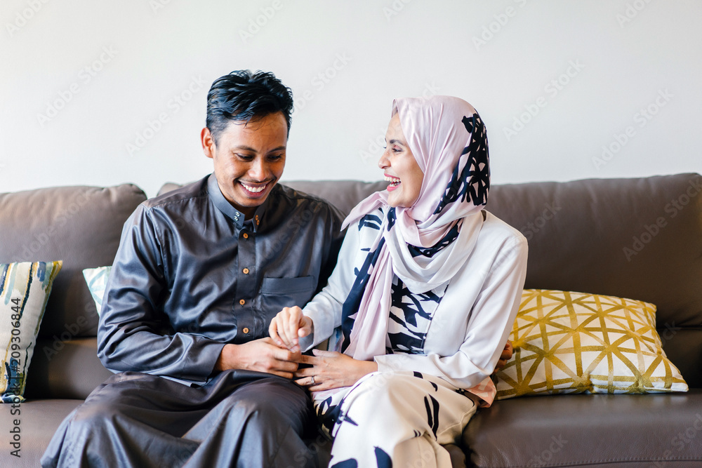 Portrait of a young Muslim couple in their home. They are dressed in ...