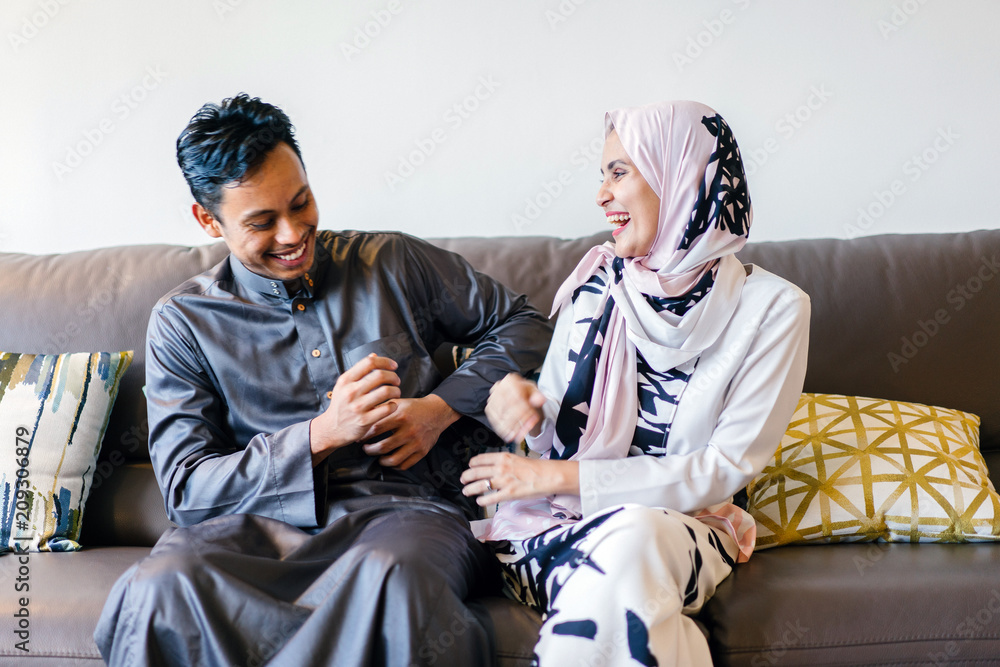 Portrait of a young Muslim couple in their home. They are dressed in ...