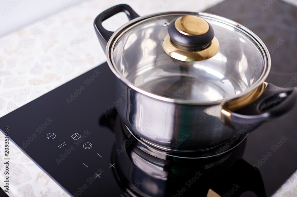 Induction stove, pot metal on it Stock Photo | Adobe Stock