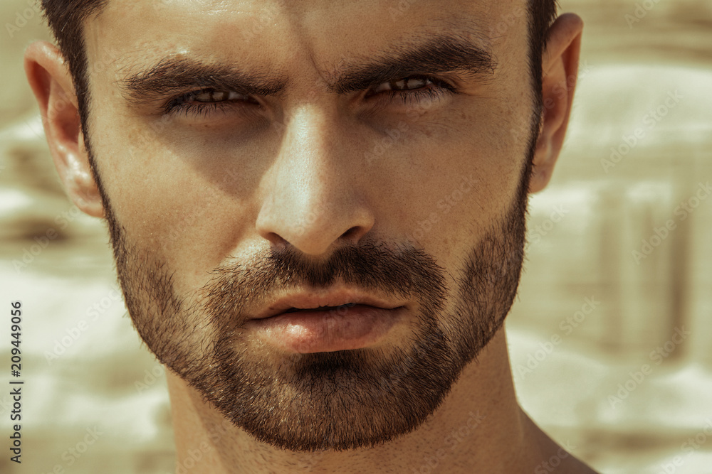 Strong face male model on the nature background with sand and water on ...