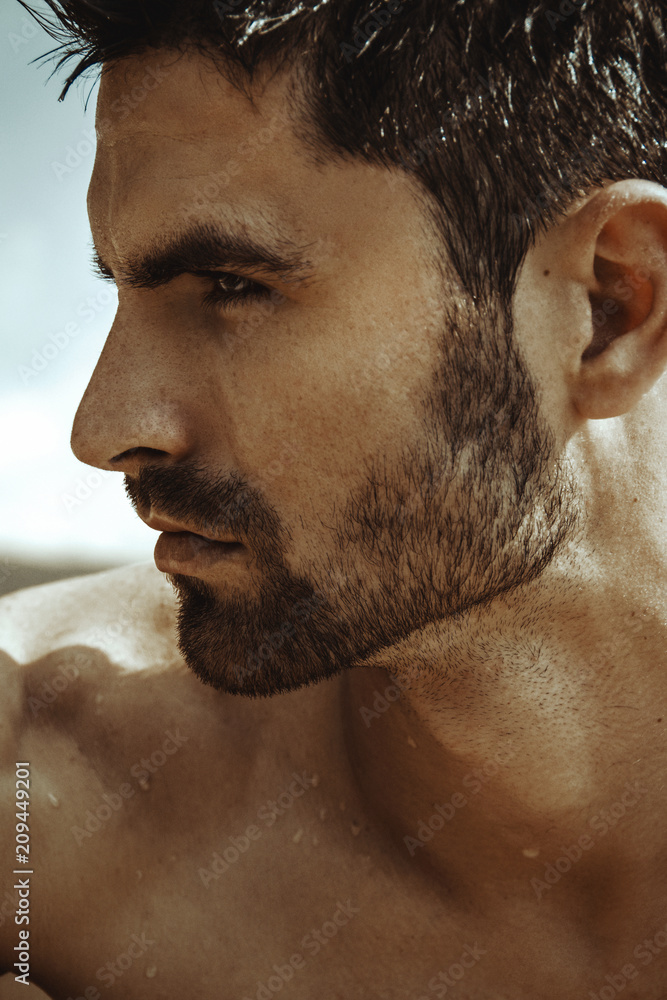 Strong face male model on the nature background with sand and water on ...