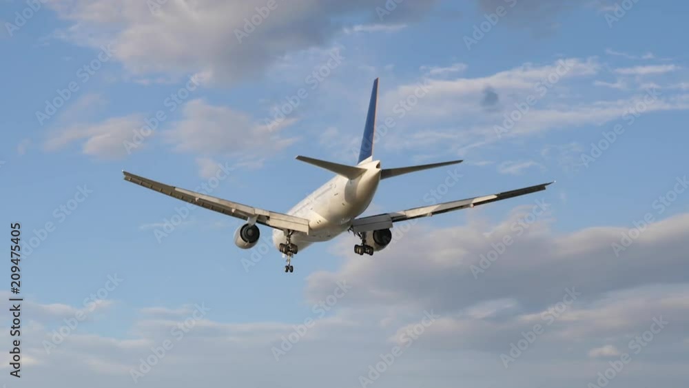 Airplane is landing back view. Plane at blue sky background with clouds ...