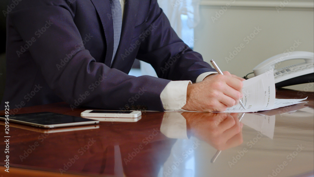 Man hand signs a paper document with ballpoint pen. Signature is fake ...
