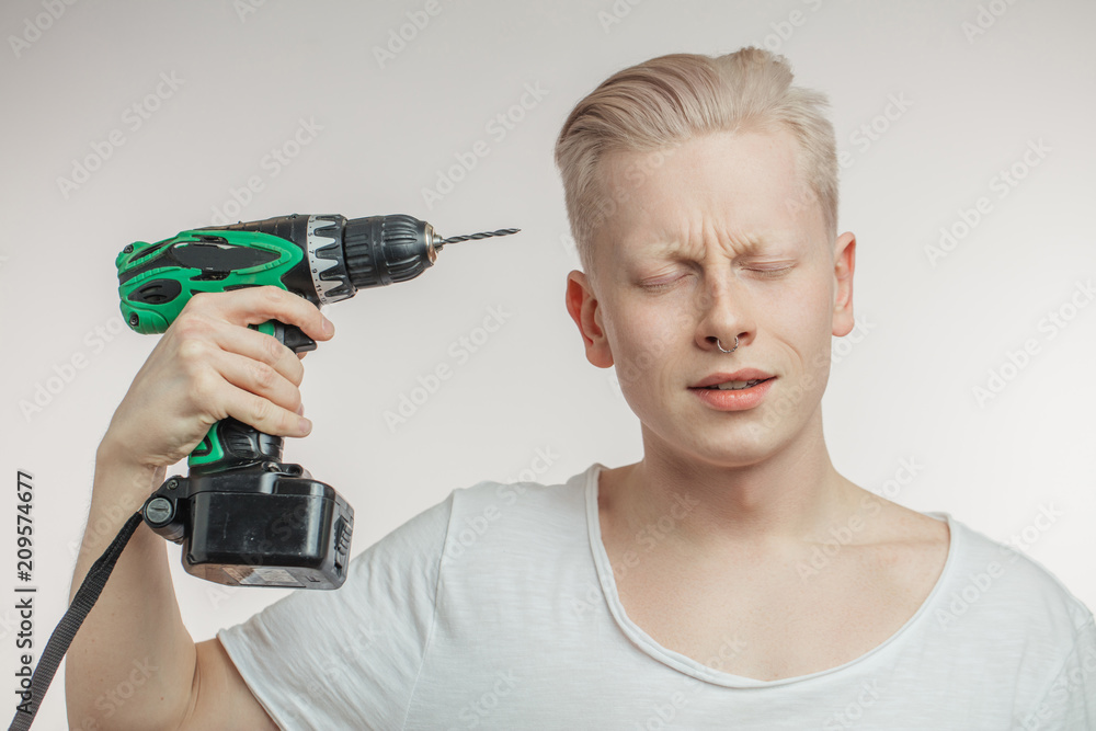 Young blonde man drilling his temple, suffering from heavy headache or ...