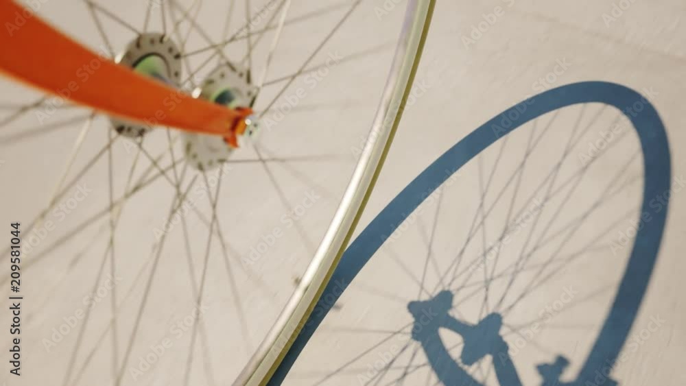 Road bike wheel spinning and casting shadow over a concrete road. Loop ...