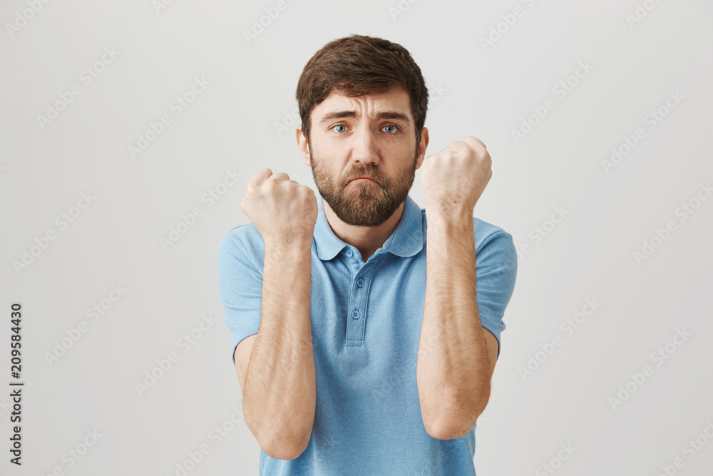 Mommy said I am strong. Studio shot of silly european guy being afraid ...