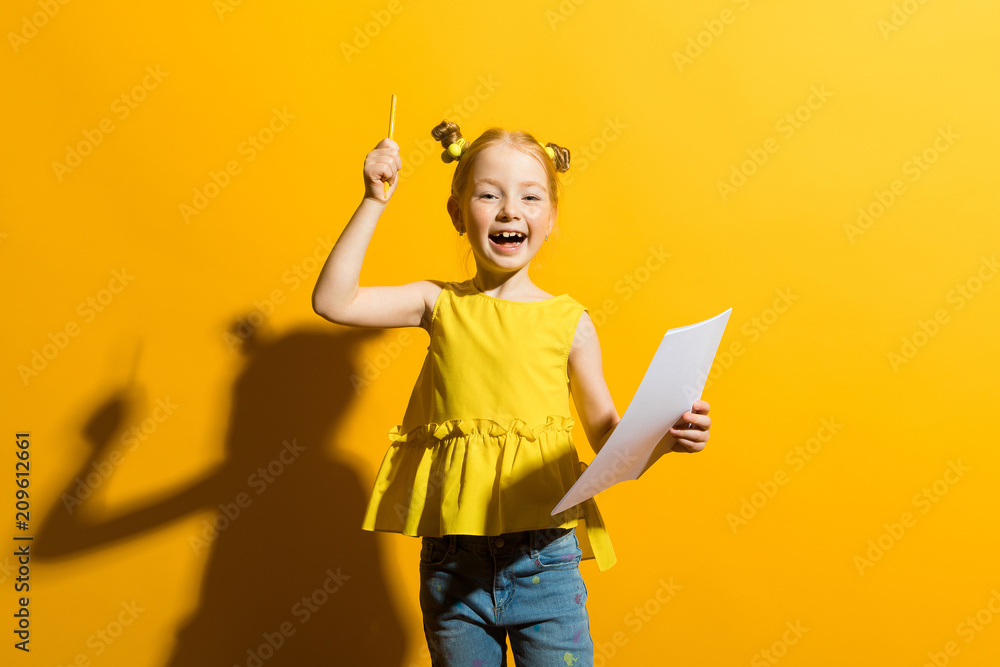 Girl with red hair on a yellow background. A beautiful girl is holding ...