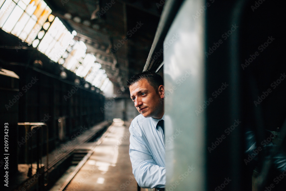 Young train driver looking outside from the cab of a diesel locomotive ...