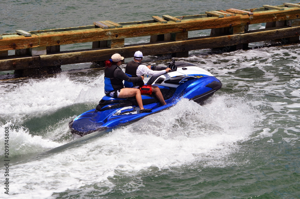 Man and a woman riding tandem on a blue and white jet ski on the ...