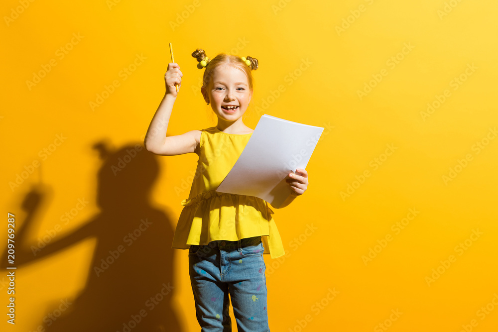 Girl with red hair on a yellow background. A beautiful girl is holding ...