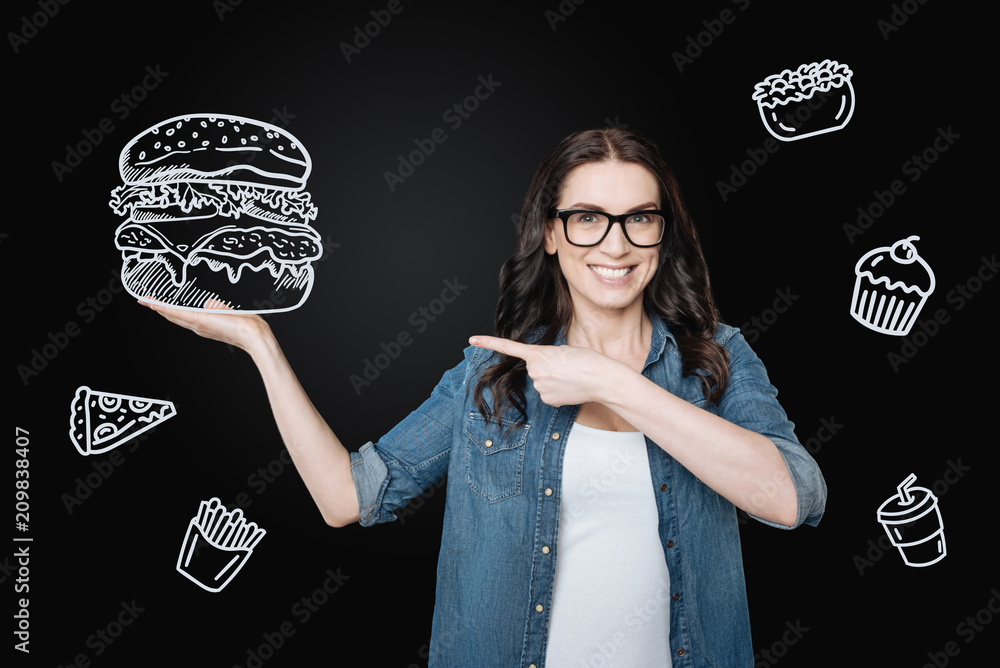 Huge hamburger. Emotional young woman feeling hungry and looking ...