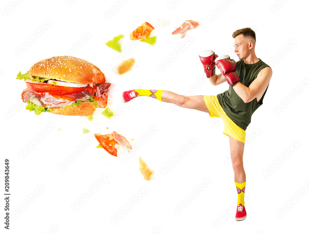 A young guy kicks a hamburgers. The concept is the fight against ...