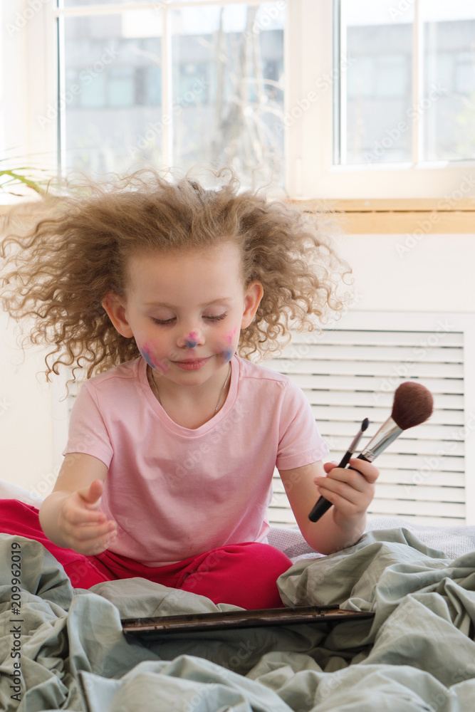 Little girl and mother's make-up. She is holding makeup brush, palette ...