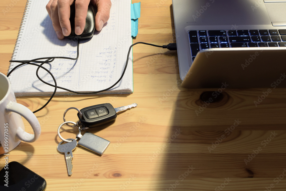 Working process with laptop, man's hand on computer mouse, car key and ...
